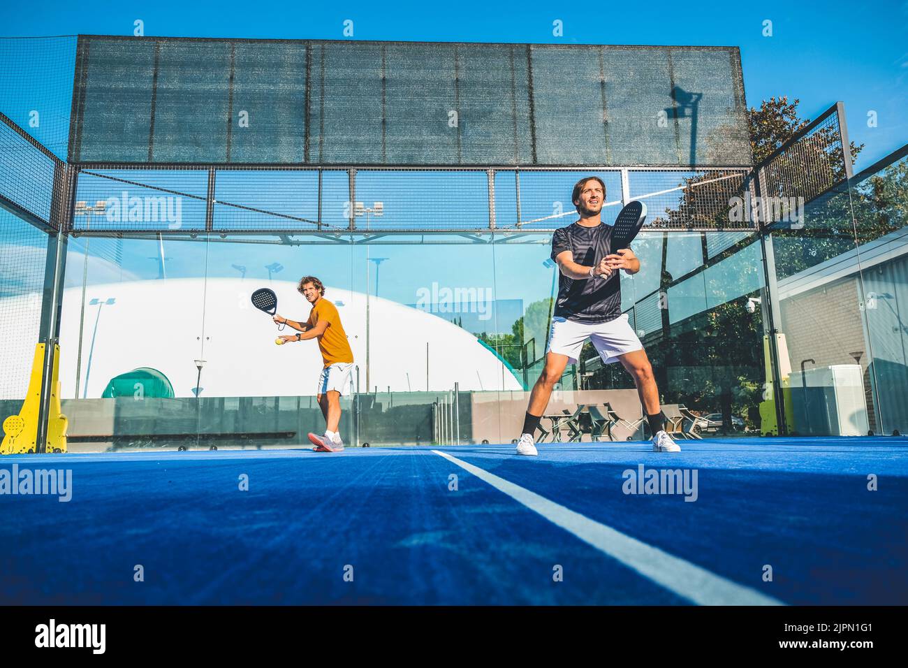 Mixed padel match in a blue grass padel court - Beautiful girl and ...
