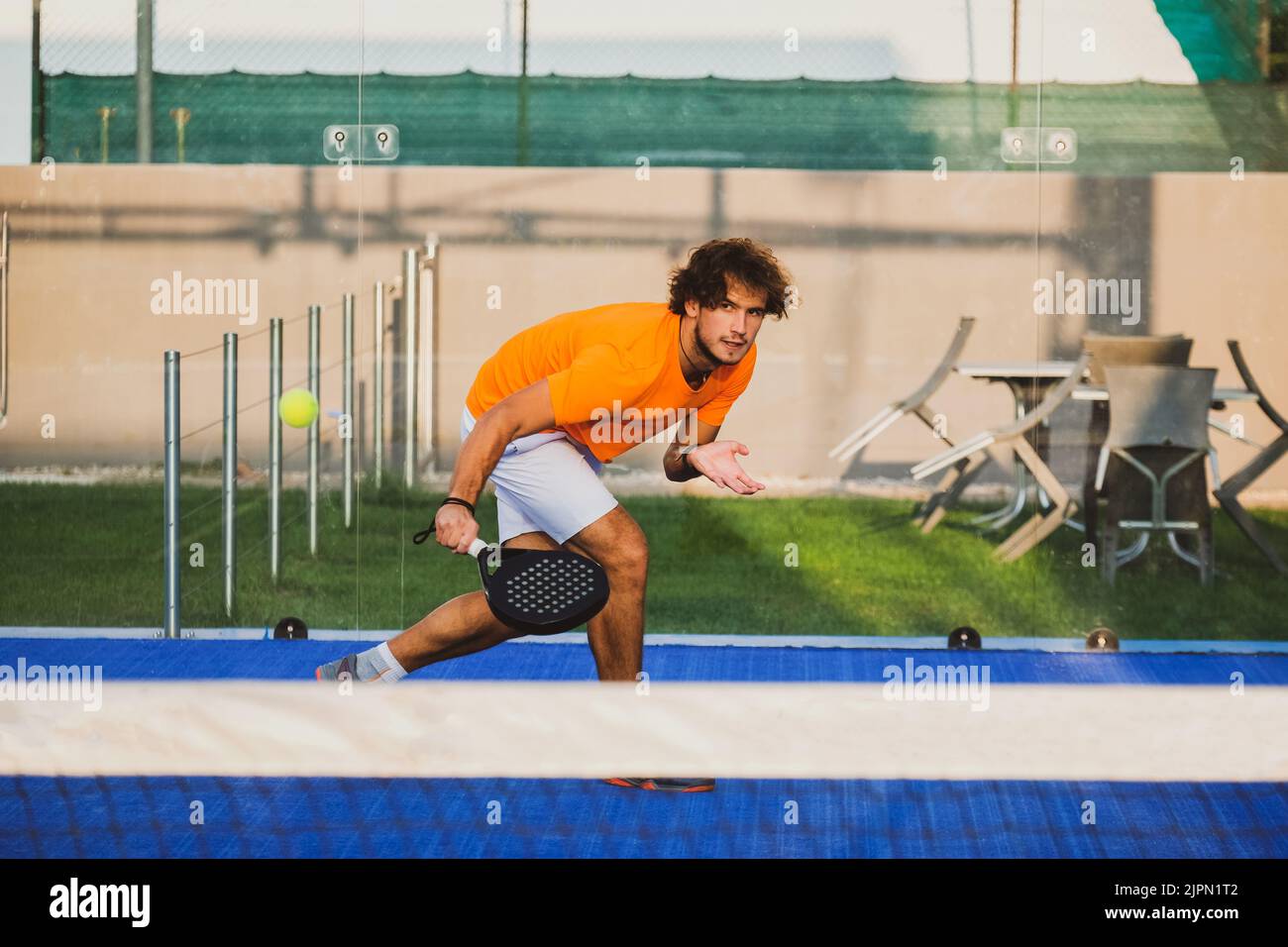 Padel match in a blue grass padel court - Handsome boy player playing a ...