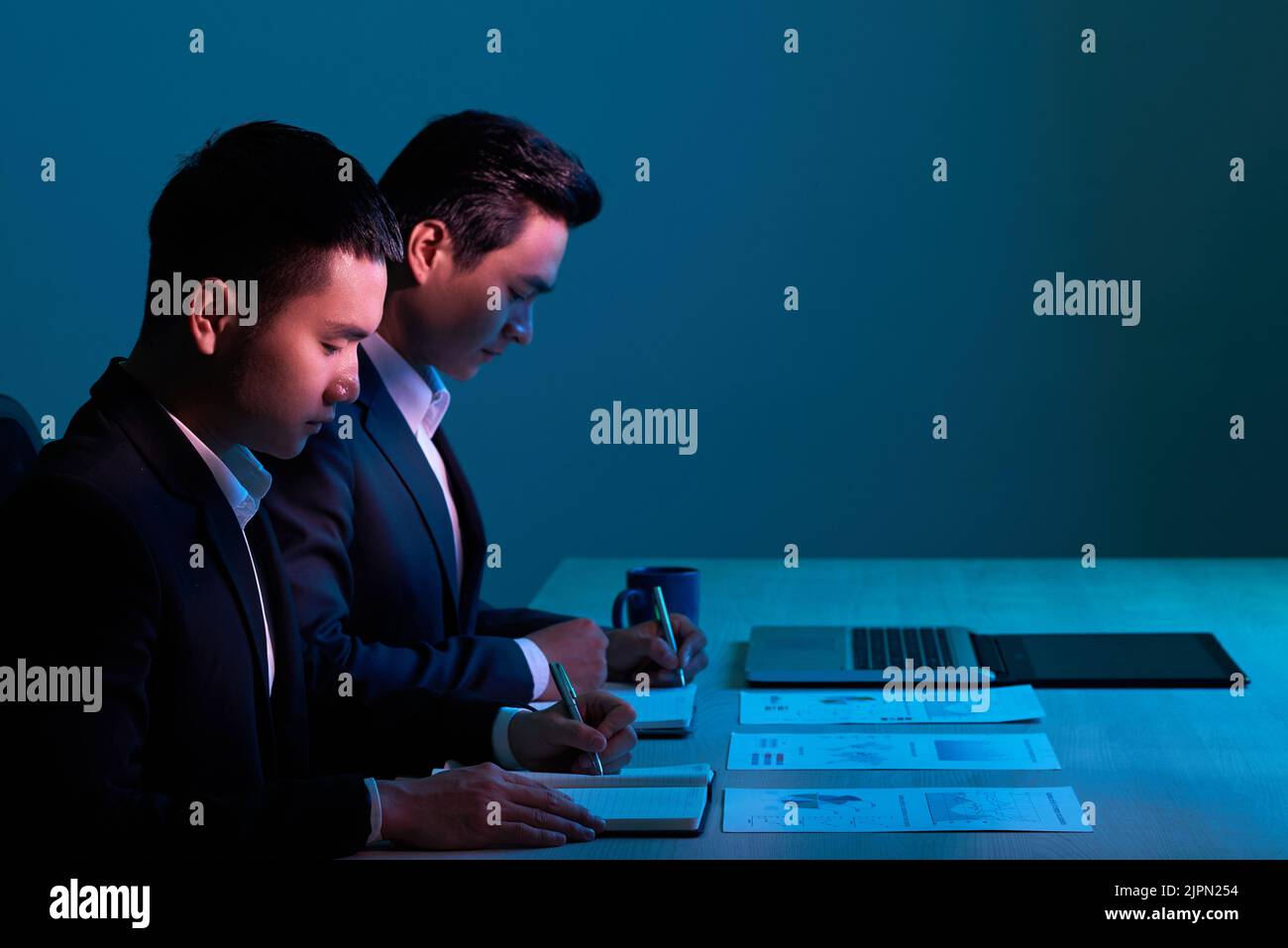 Business people analyzing financial charts and writing down conclusions ...