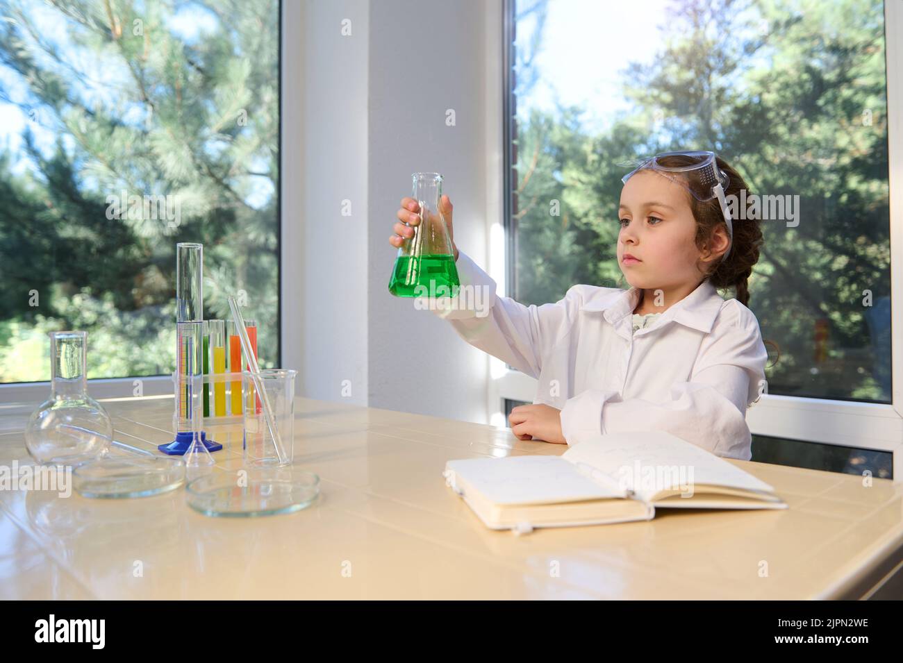 Little future chemist scientist holding a flat bottomed flask with ...