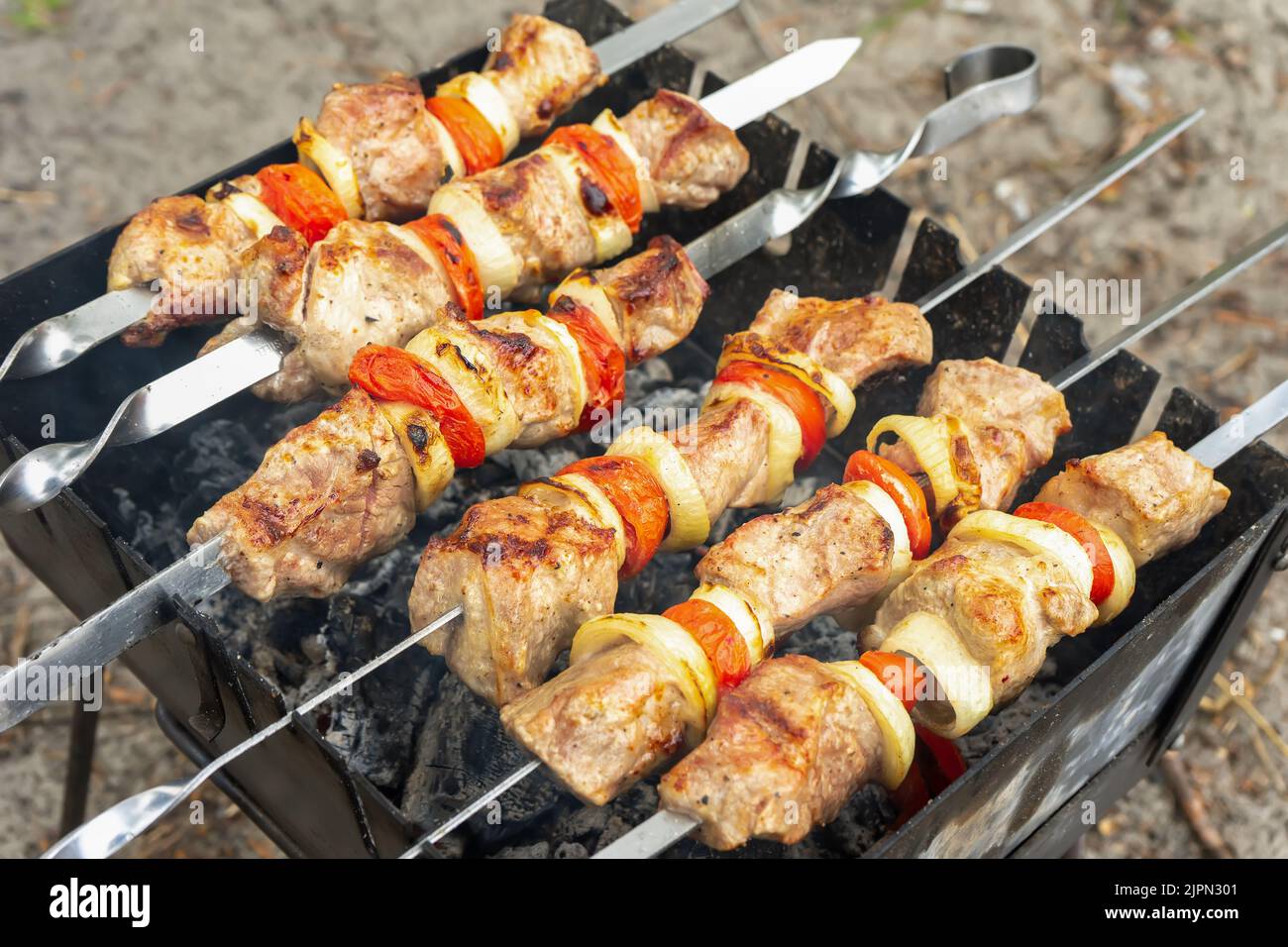 Grilled fried pork meat, pieces of meat on skewers. Process of cooking ...