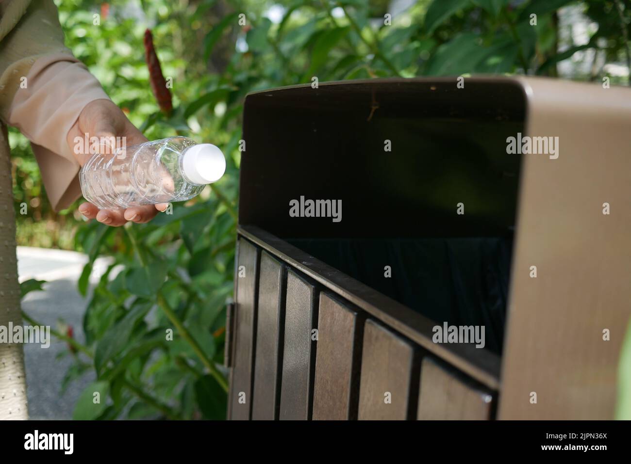 women hand throwing an empty plastic water bottle in the garbage trash ...