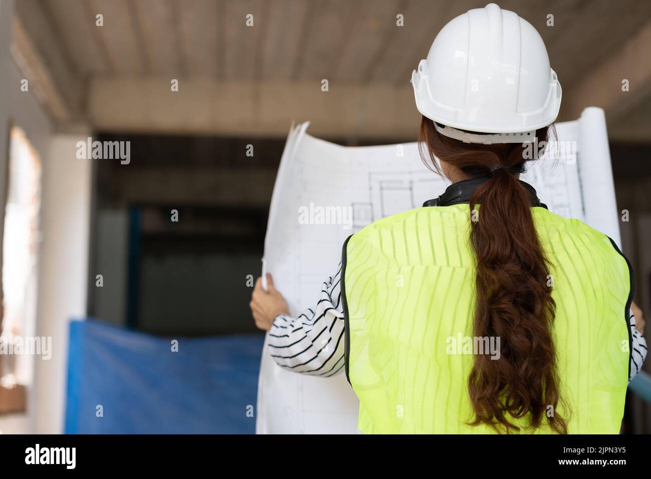 Asian engineer or Young woman Architect put on a helmet for safety and ...