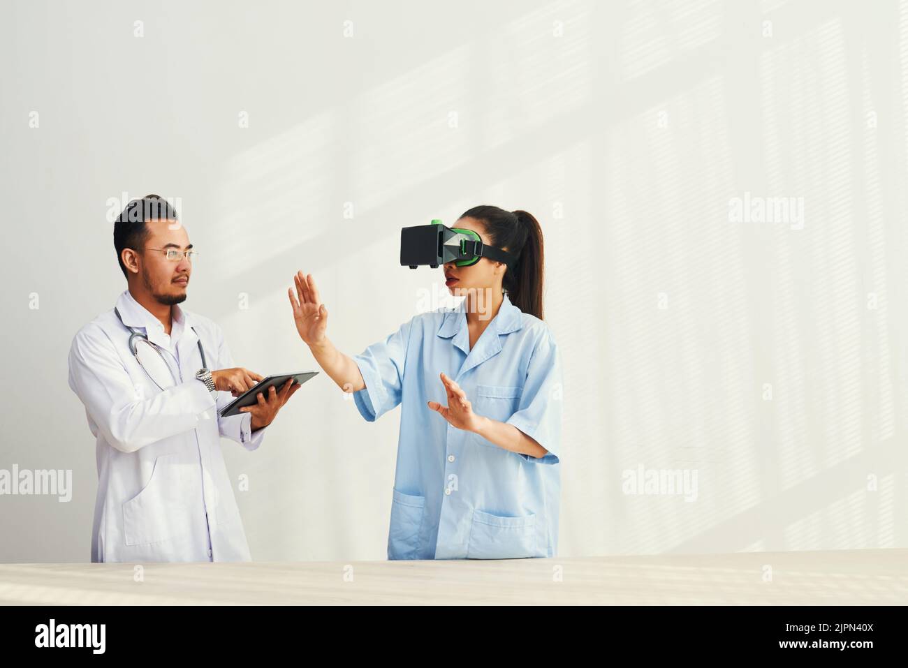 Unrecognizable young nurse wearing uniform using VR headset while ...