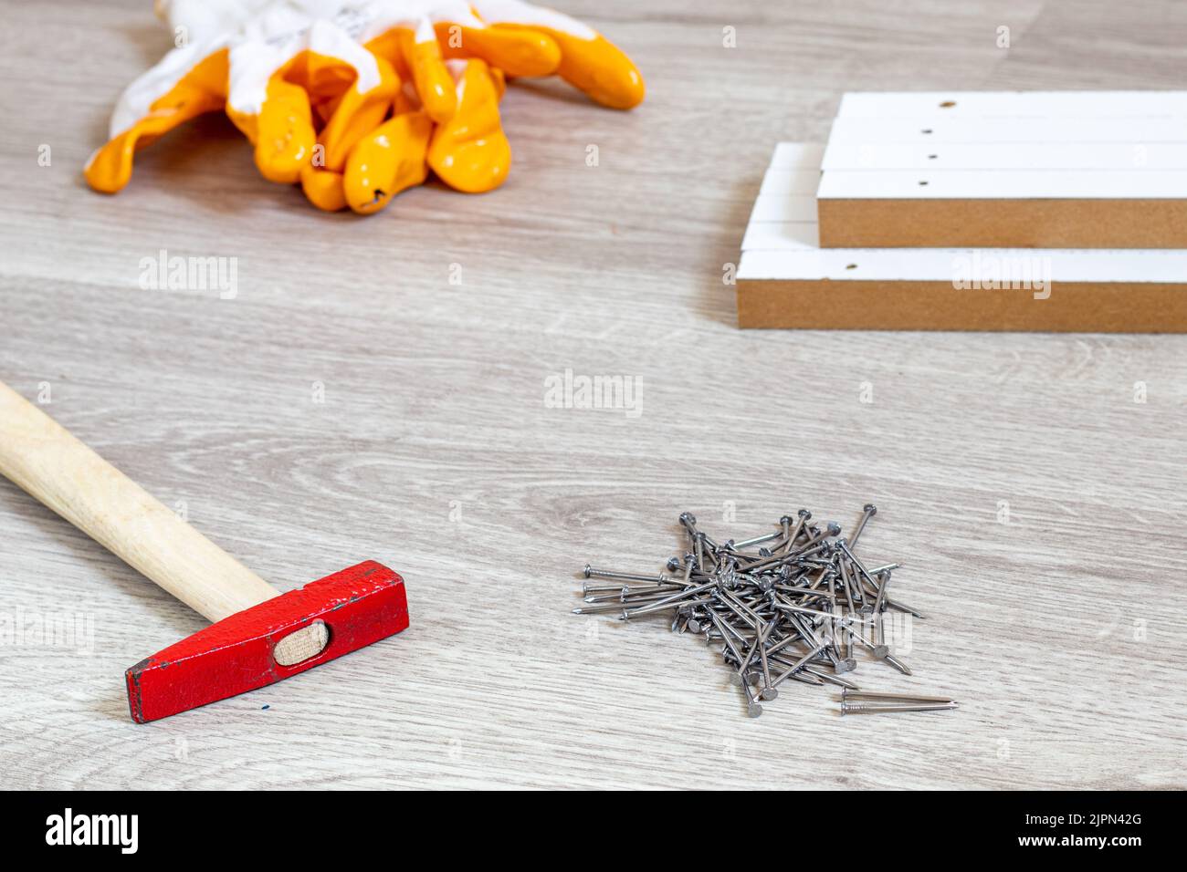 Construction tools on the ground; Hammer, nails, gloves and chipboard ...