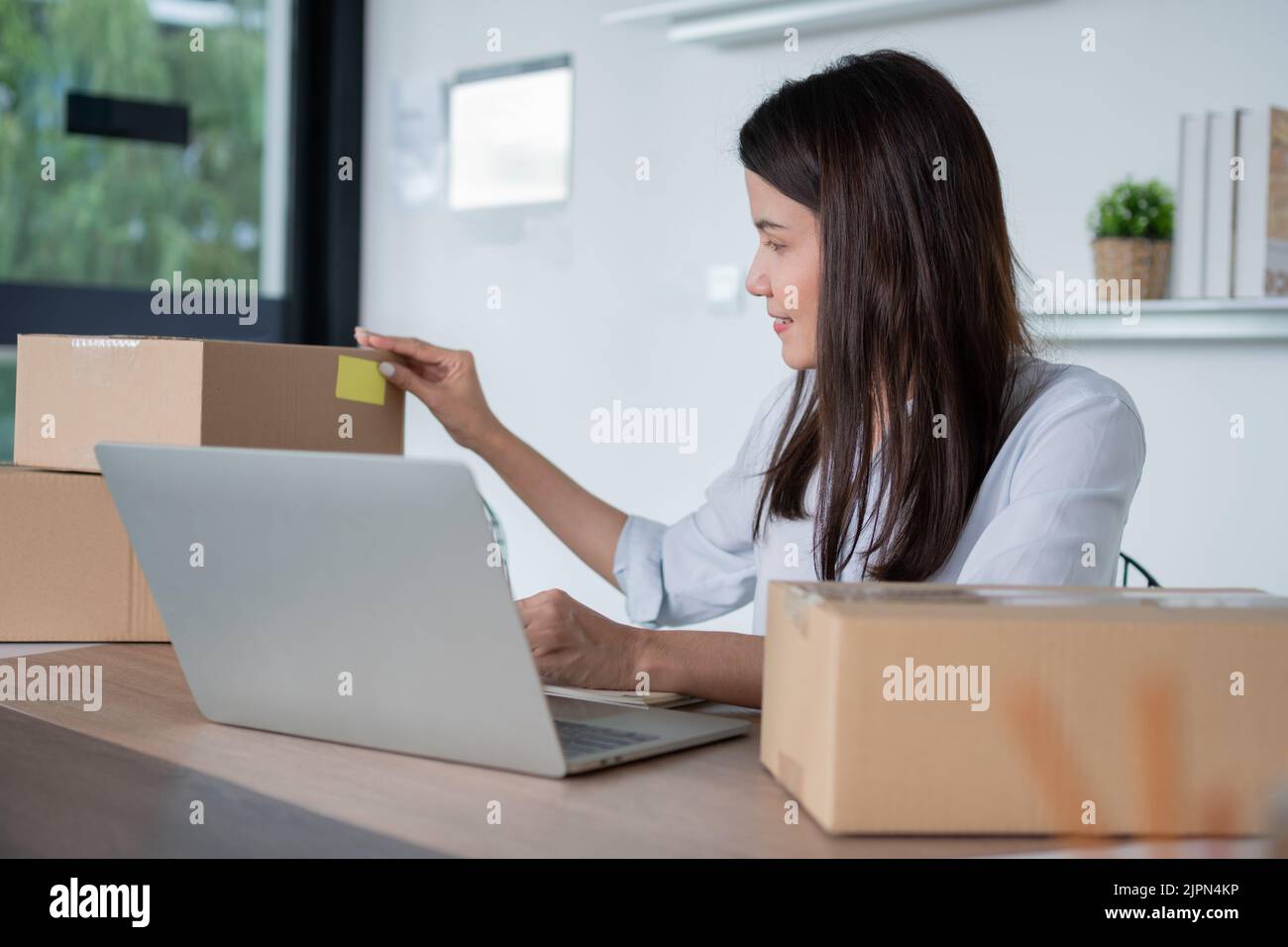 Happy young Asian woman entrepreneur, Take note after check order and ...