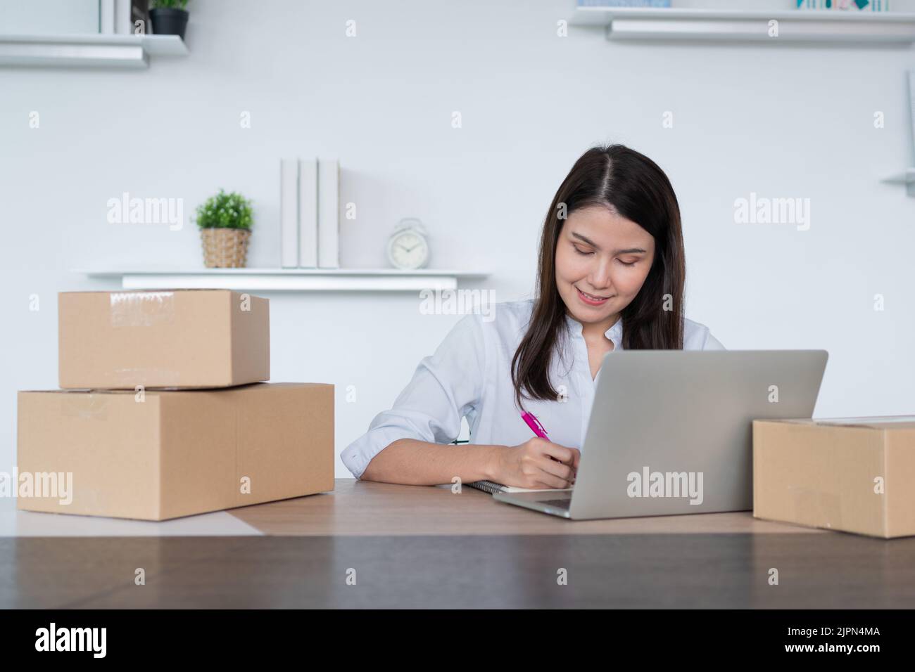 Happy young Asian woman entrepreneur, Take note after check order and ...