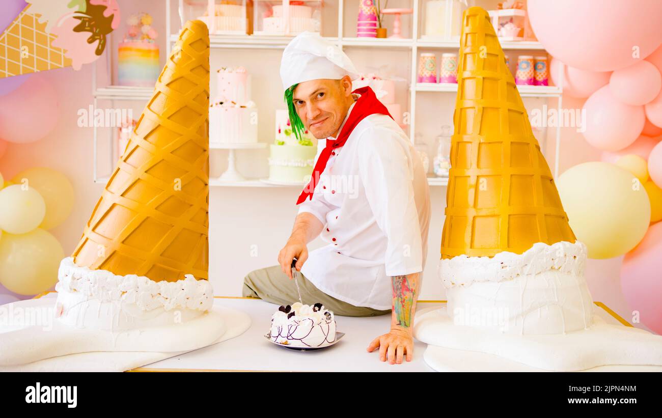 Chef cutting cake in confectionery. Content male confectioner cutting ...