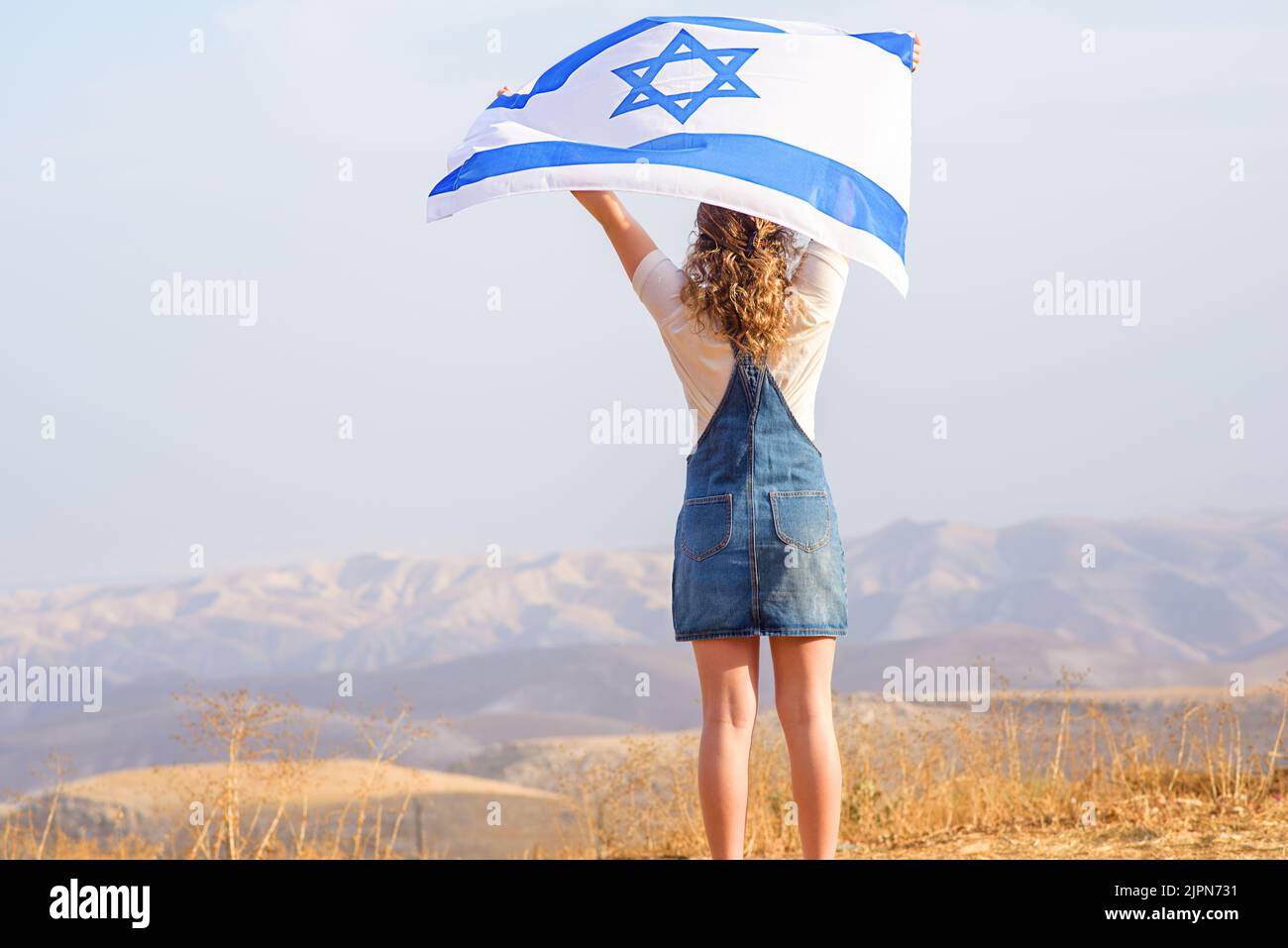 Teen curly hair Jewish girl standing with the flag of Israel on the ...