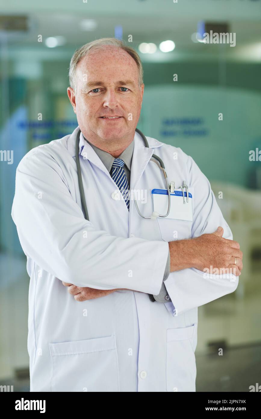 Portrait of experienced confident doctor standing with his arms crossed ...