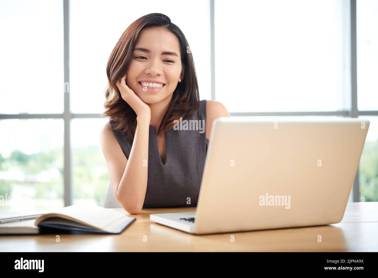 Beautiful young business lady smiling when reading e-mail on laptop ...