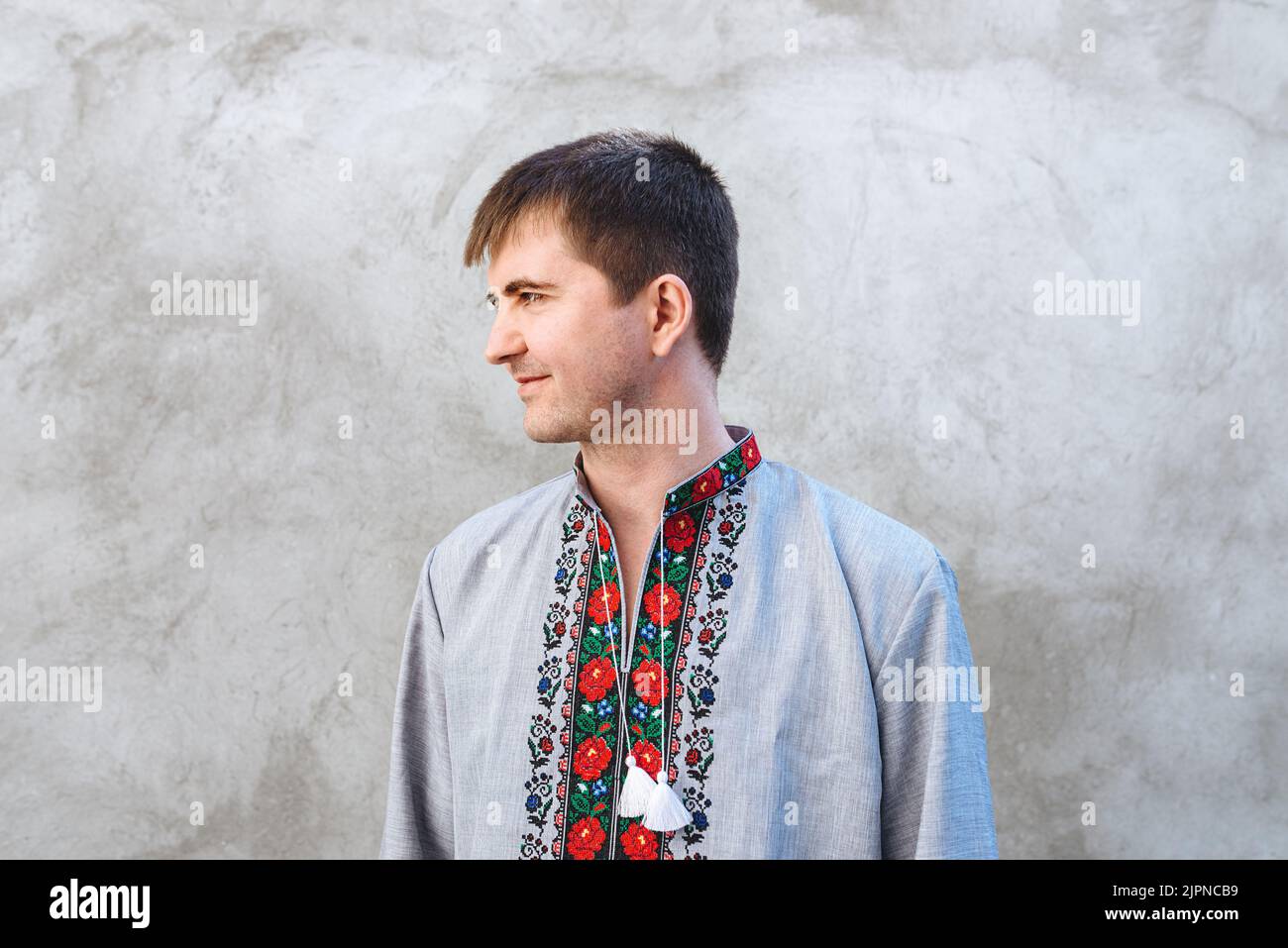 Portrait of man in embroidered Ukrainian shirt. Guy looks away against ...