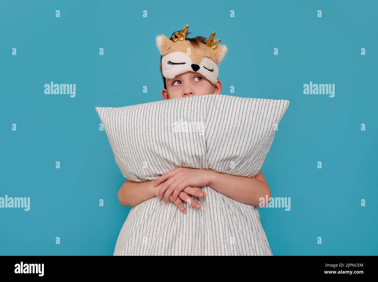 A cunning boy in a sleep mask on a blue background hugs a pillow, copy-paste Stock Photo - Alamy