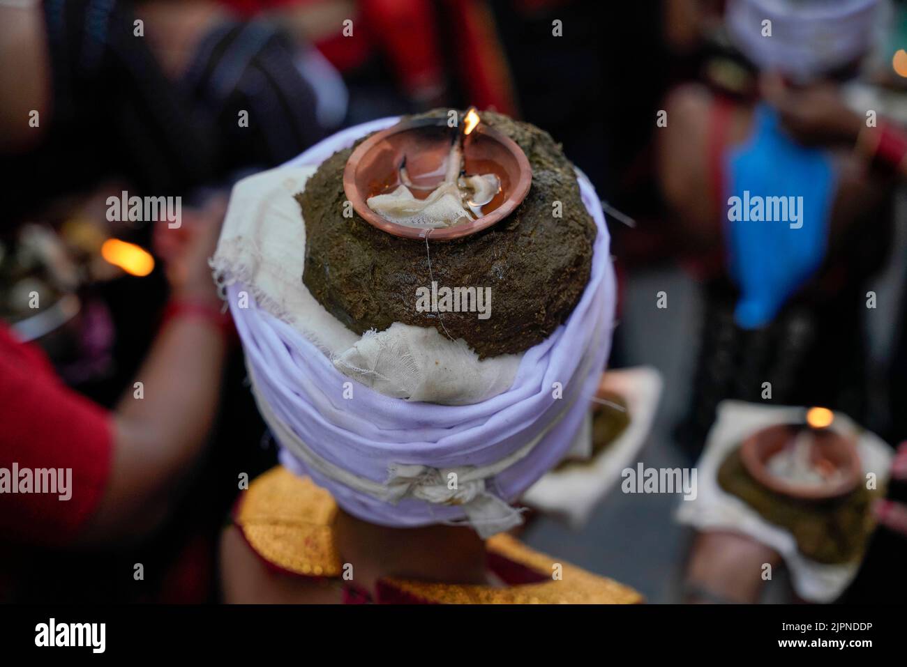 A devotee with lit oil lamps on his head and shoulders takes part in a ...