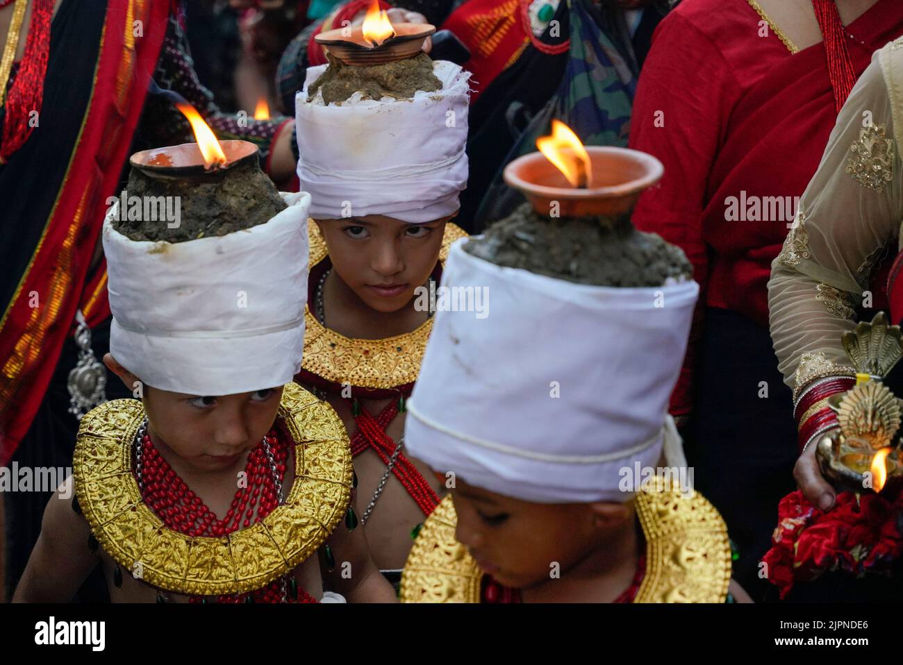 Young devotees with lit oil lamps on their heads and shoulders take ...