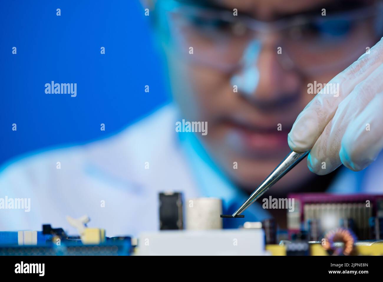 Close-up image of engineer putting chip on electronic circuit board ...