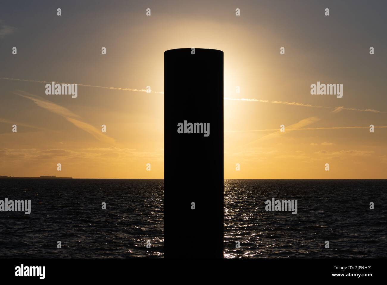 Sun setting behind a pole reflecting in the water Stock Photo - Alamy