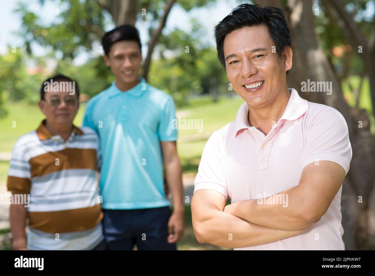 Happy middle-aged man, his aged dad and teenage son in the background ...