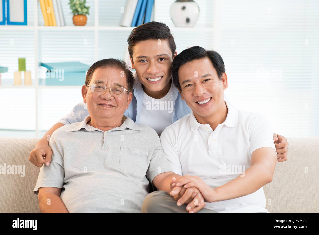 Smiling teenage man hugging his father and grandfather Stock Photo - Alamy