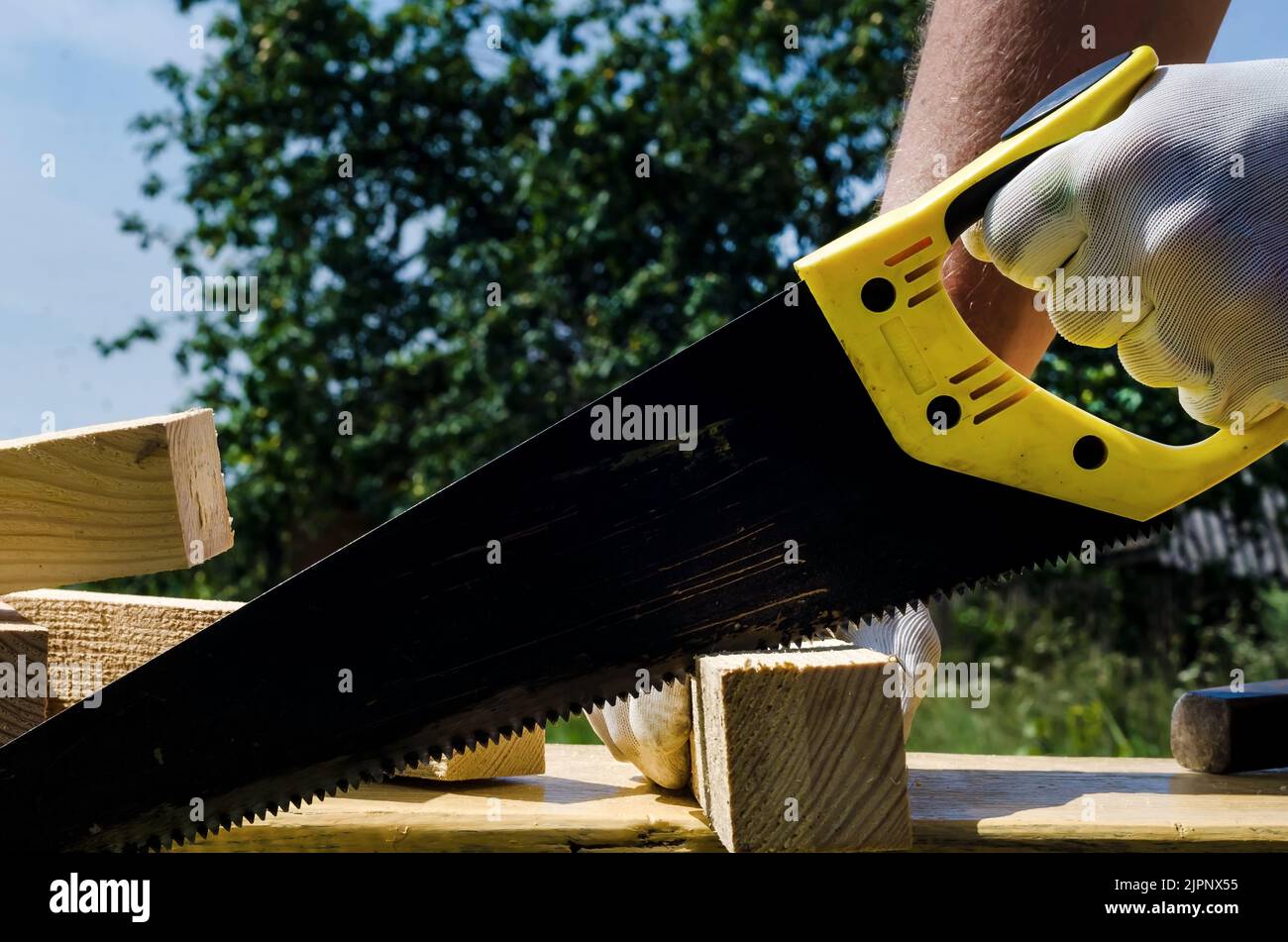 A hand with a hacksaw cuts a wooden board or beam. Construction Stock ...