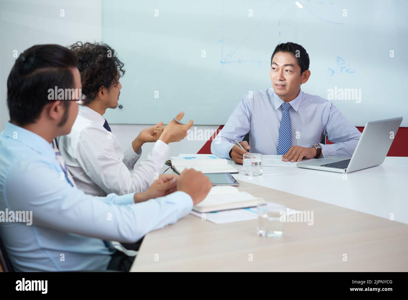 Mature Vietnamese employee listening to ideas of his coworkers Stock ...