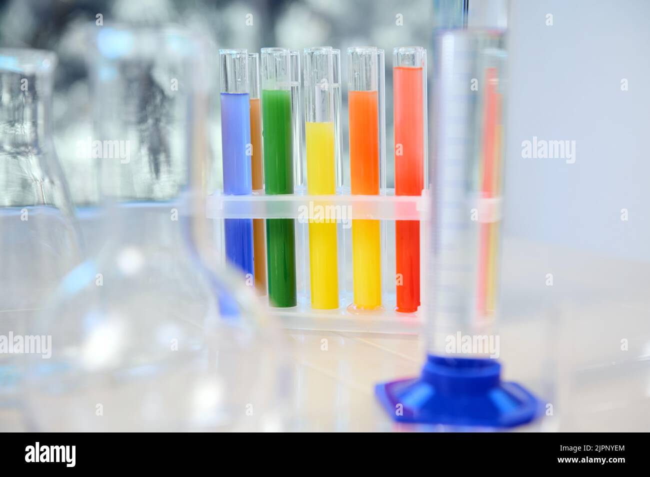 Focus on test tubes with rainbow colored chemicals standing on tripod ...