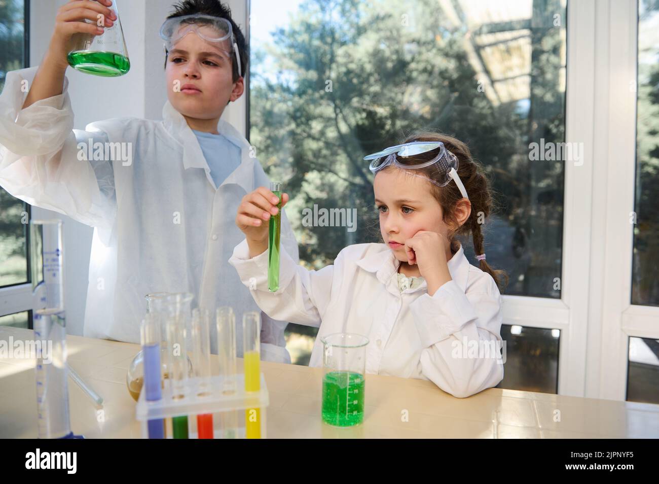 Serious students standing at the table, observing the chemical reaction ...