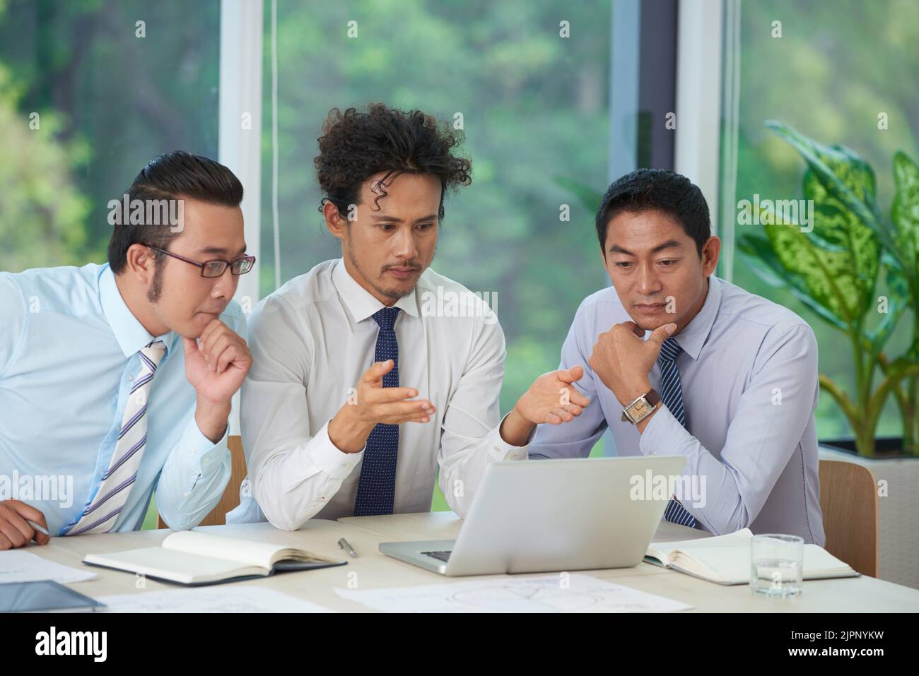 Serious Asian business executives reading e-mail with important ...