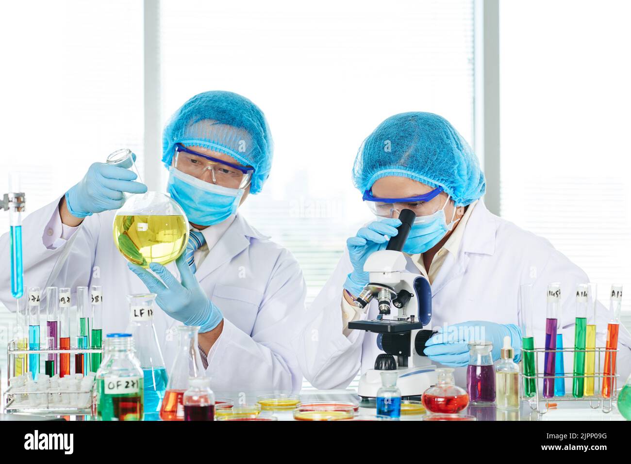 Group of talented Asian researchers wearing safety goggles and rubber ...