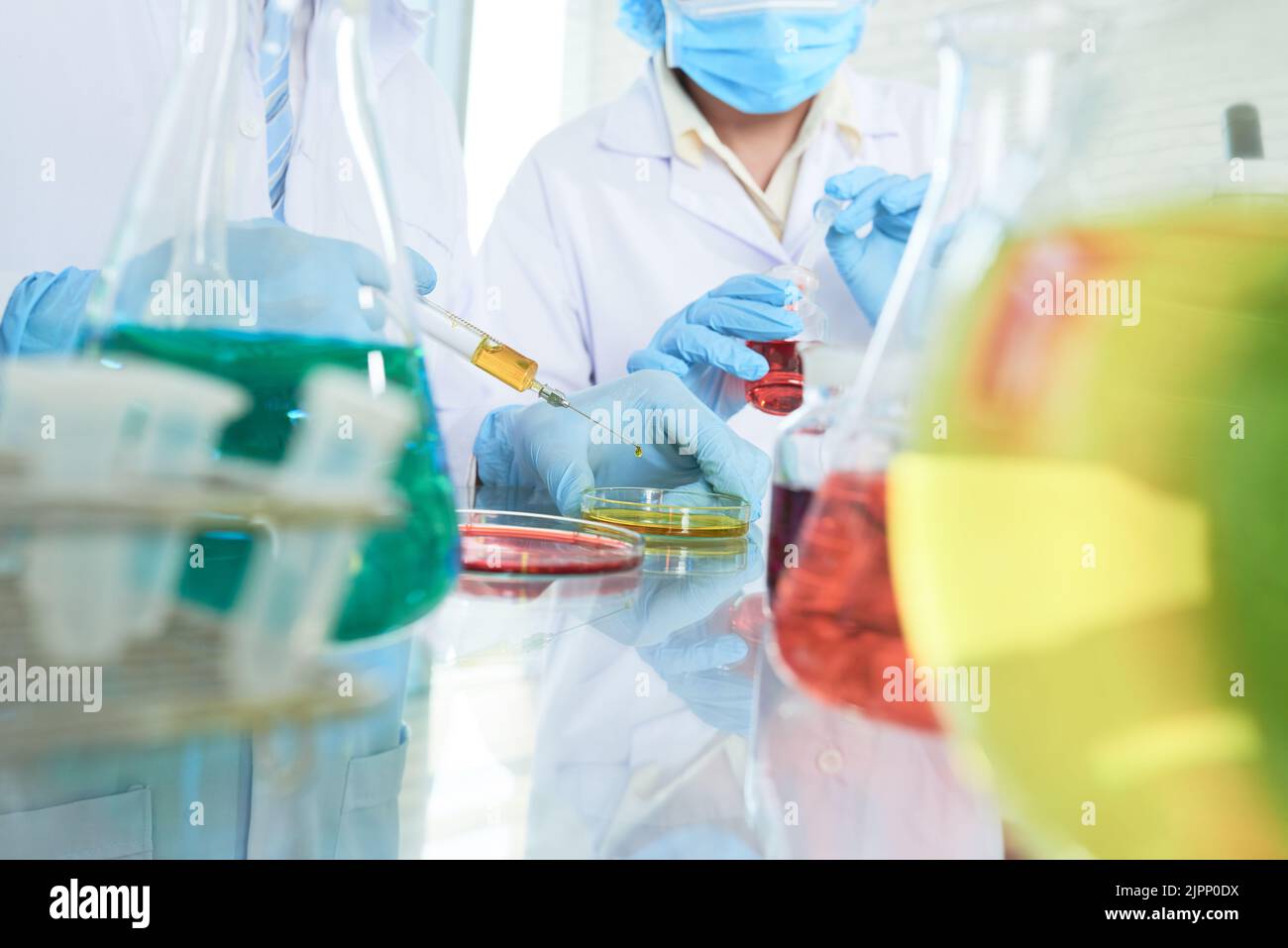 Group of scientists wearing rubber gloves and white coats standing at ...