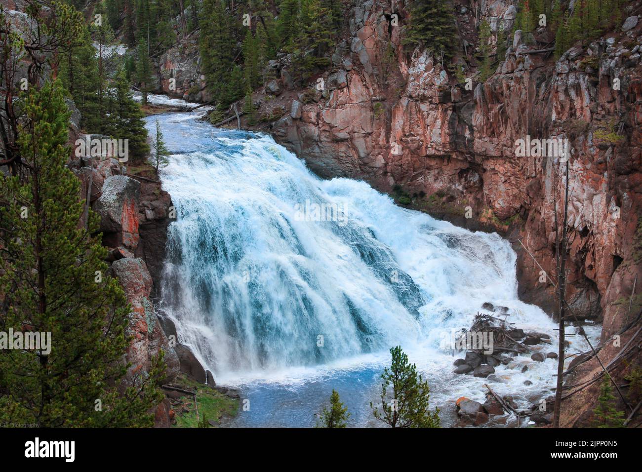 A raging waterfall surrounded by trees and rocks Stock Photo - Alamy