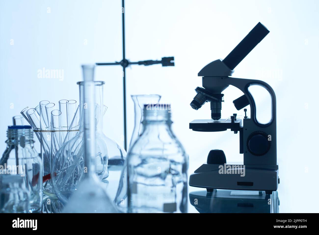 Laboratory bench with modern microscope, test tubes, glass bottles and ...