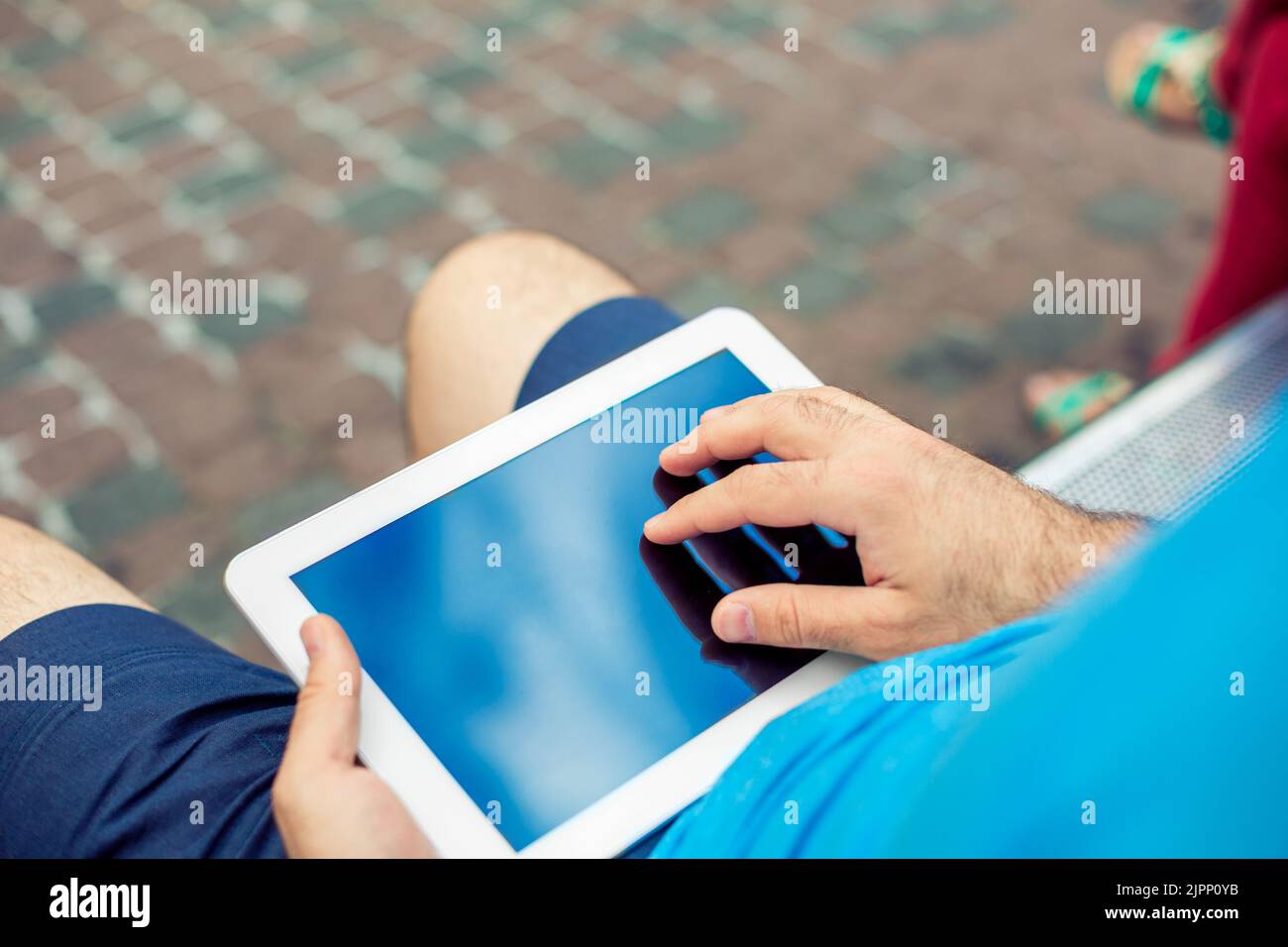 Man sitting on a bench and using a digital tablet Stock Photo - Alamy