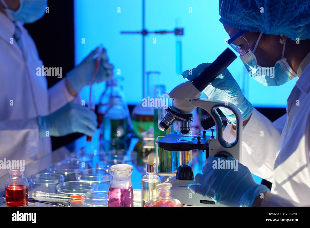 Working process at dim laboratory: group of talented scientists gathered together at bench and ...