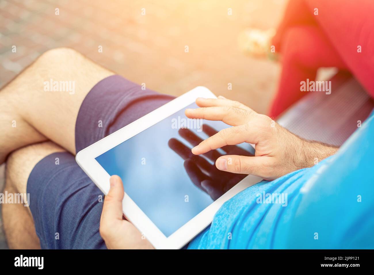 Man sitting on a bench and using a digital tablet Stock Photo - Alamy