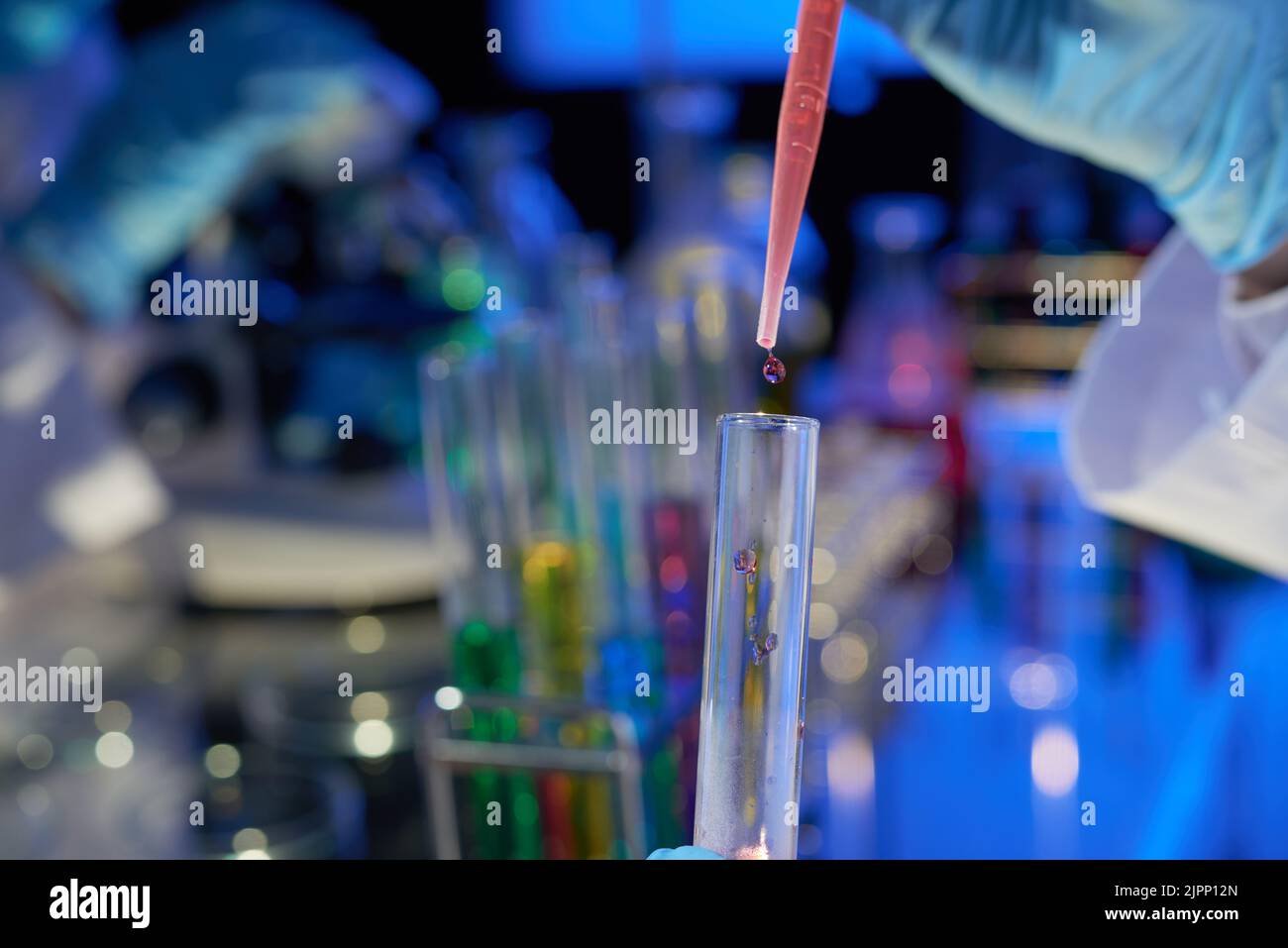Extreme close-up of unrecognizable scientist pouring liquid into test ...
