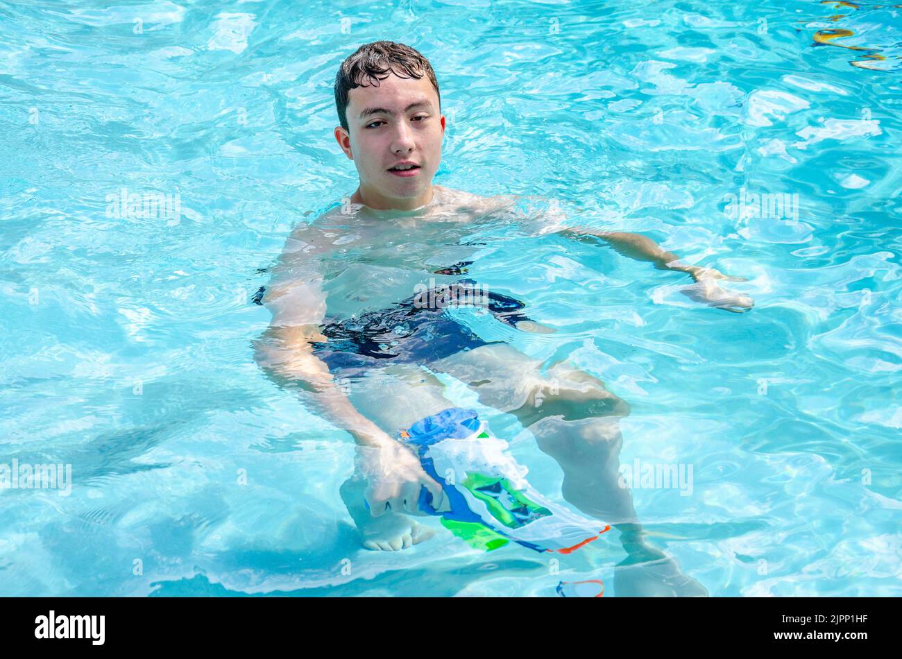 A teenage boy relaxing in a swimming pool Stock Photo - Alamy