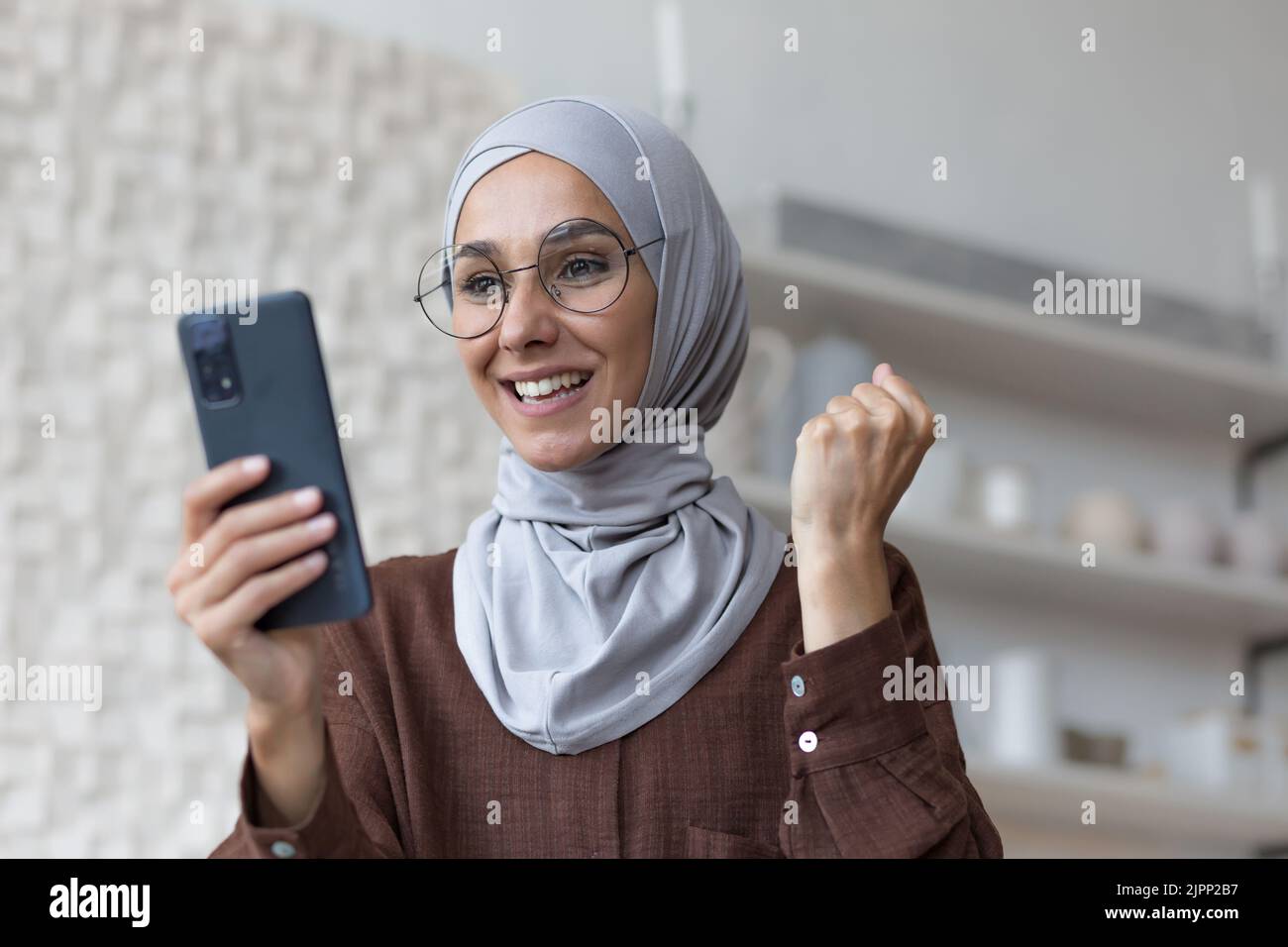 Young beautiful arab woman using phone smiling and celebrating success ...