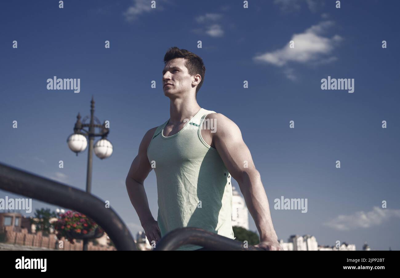 Man bodybuilder posing on blue sky Stock Photo - Alamy