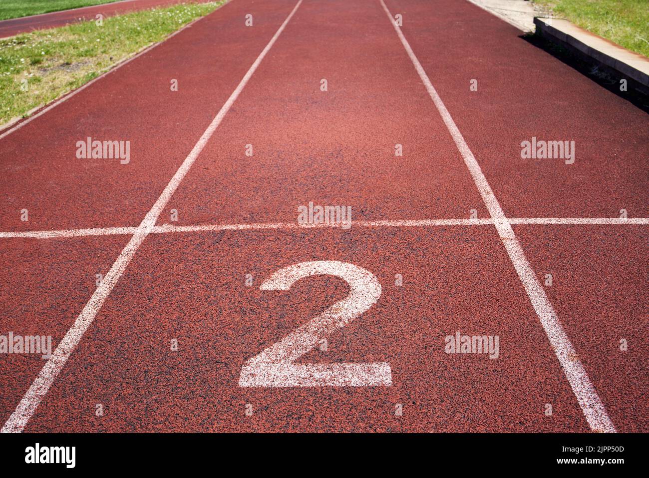 Empty red running lane with number two on it Stock Photo - Alamy