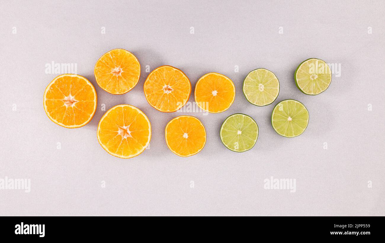 Creative summer background with sliced limes and lemons on grey theme ...