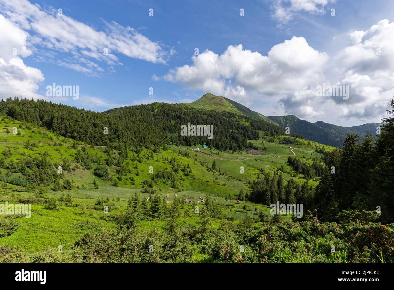 A road in the mountains that runs along the slope among meadows and ...