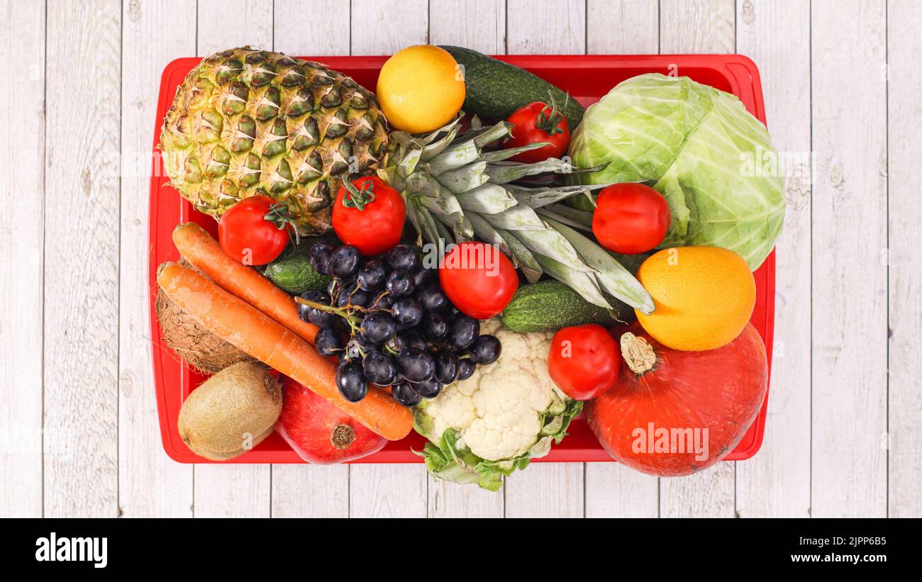 Red plate full with healthy food. Fresh fruits and vegetables on wooden ...