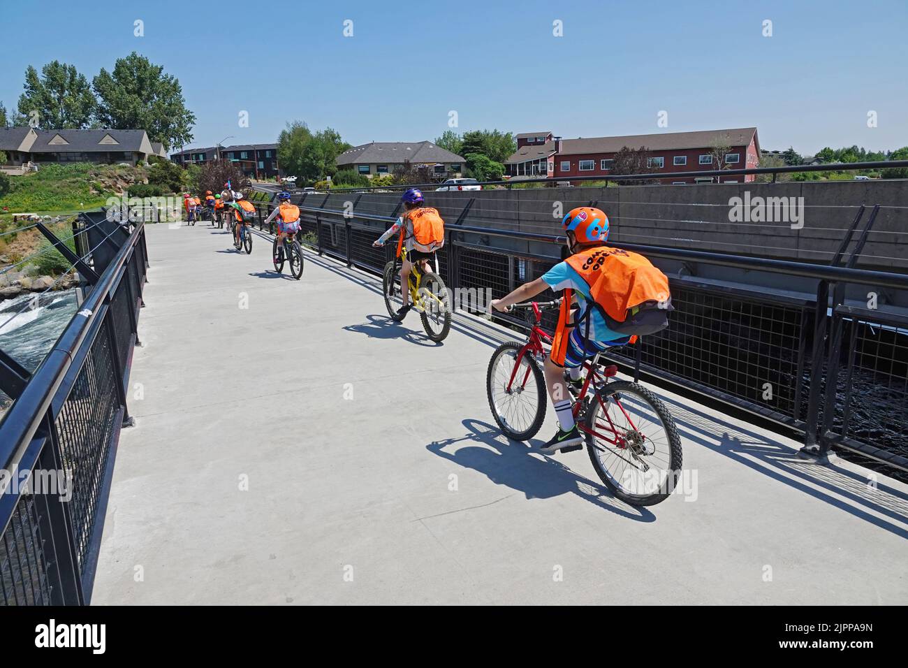A string of young bike riders ride a scenic bike path along the ...