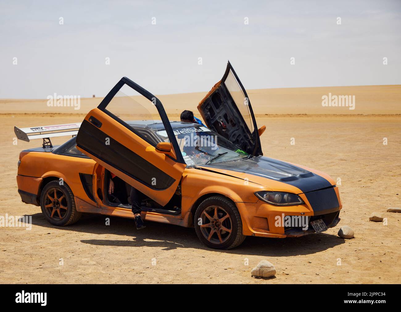 An orange sportscar in the desert with open doors Stock Photo - Alamy