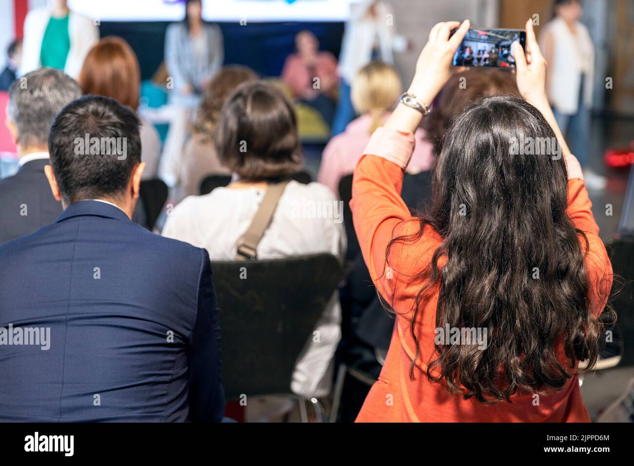 Business conference or presentation, female participant photographing ...