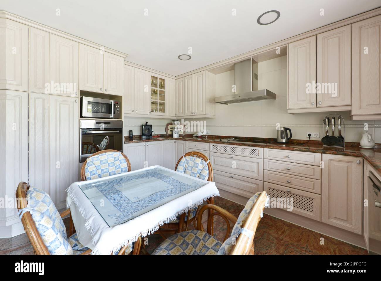 Front view of a kitchen with pale pink wooden cabinets on all walls ...