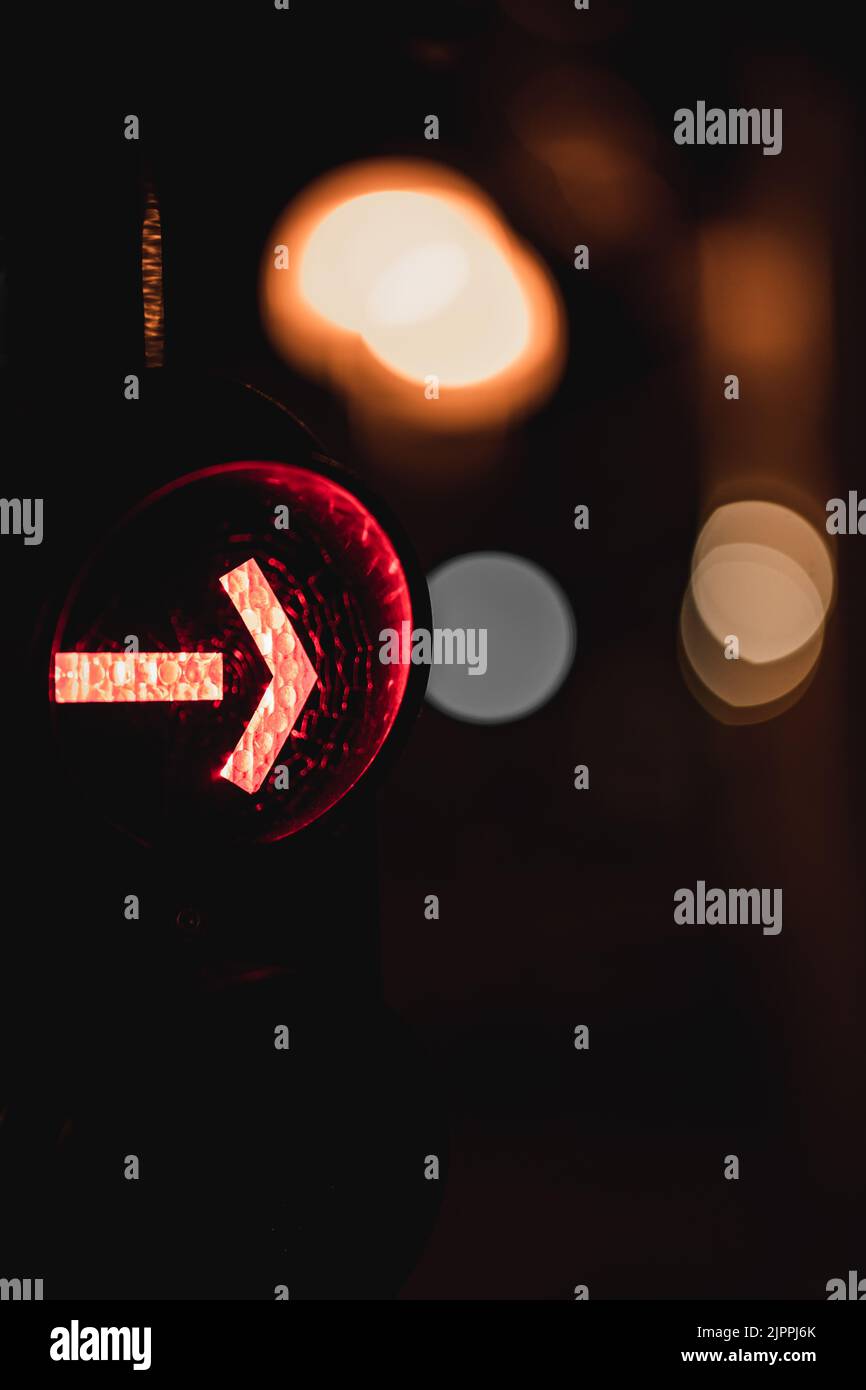 A closeup shot of a red traffic light with an arrow on a blurry bokeh ...