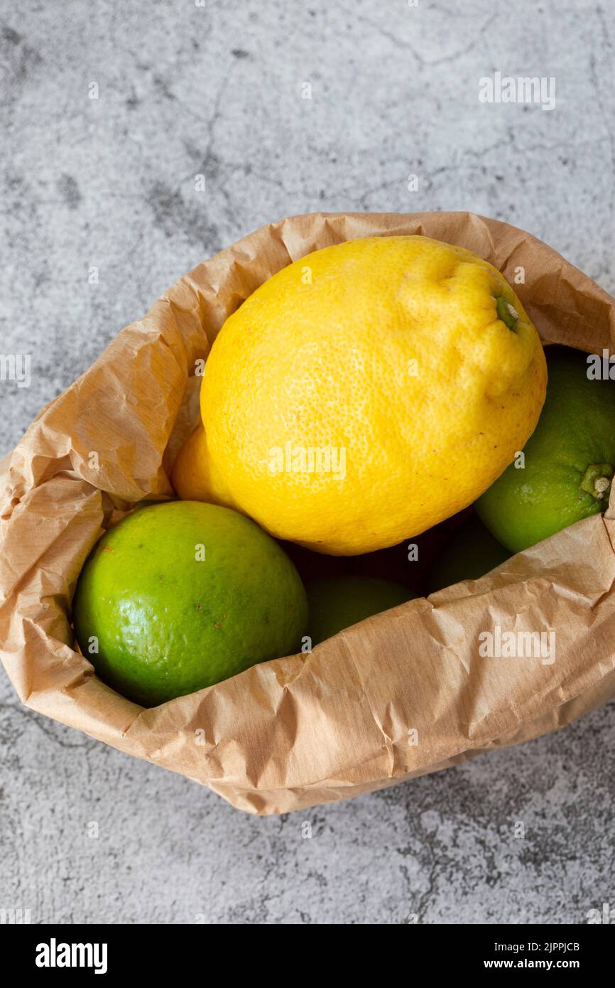 Lemon and lime in a brown paper bag on a concrete background. Eco ...