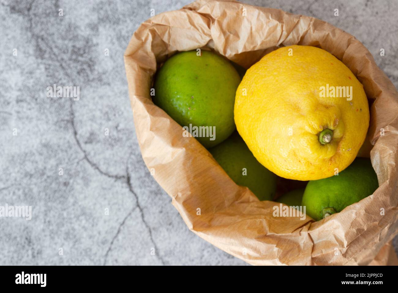 Lemon and lime in a brown paper bag on a concrete background. Eco ...